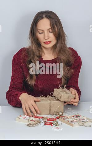 Woman with Christmas gift boxes on grey background Stock Photo - Alamy