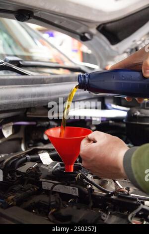 Worker adding oil to car Stock Photo - Alamy
