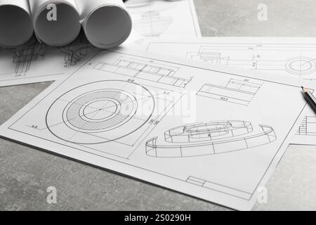 Different engineering drawings on gray textured table, top view. Space ...
