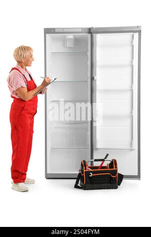 Female worker with clipboard near refrigerator on white background ...