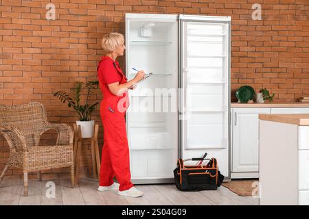 Female worker with clipboard near fridge in kitchen Stock Photo - Alamy