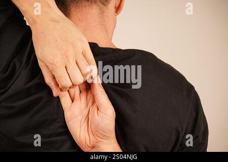 Hands locked behind the back against the background of a black T-shirt ...