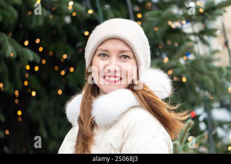 A woman stands near a Christmas tree with festive ornaments Stock Photo ...