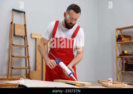 Worker with caulking gun glueing wooden plank indoors, closeup Stock ...