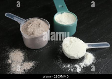 Protein powders in scoops on dark textured table, space for text Stock ...