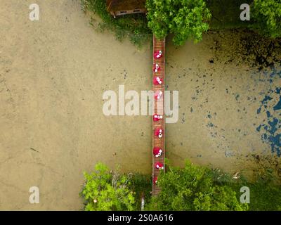 An aerial perspective shows a wooden bridge crossing water, leading to ...