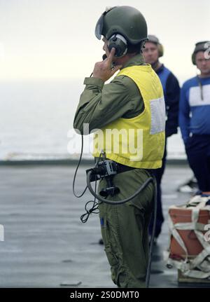 An Aircraft Handler in a yellow shirt, signals the launch of a F/A-18 ...