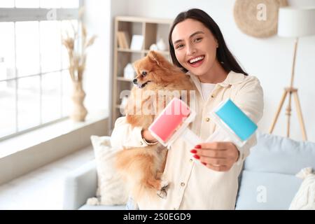 Young woman with fluffy dog and lint roller on white background Stock ...