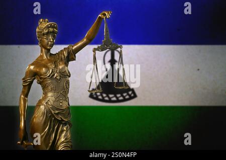 Lesotho flag with statue of lady justice and judicial scales in dark ...