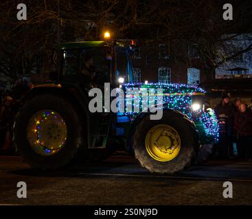 A tractor decorated with colorful Christmas lights drives through a ...