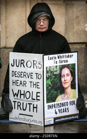A supporter of Defend Our Juries holds a photo sign of four climate ...