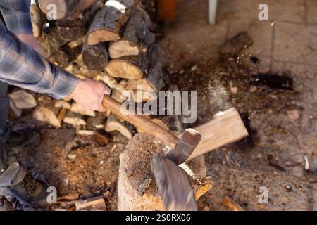 A dynamic action shot of a man splitting a log with an axe on a tree ...