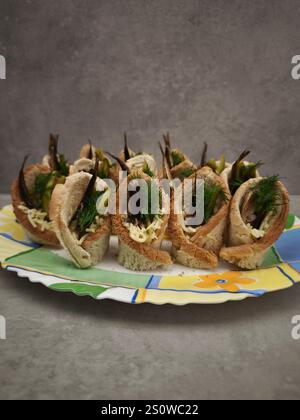 Small fish canapes with sprats, dill, gherkins, and cheese, arranged on ...