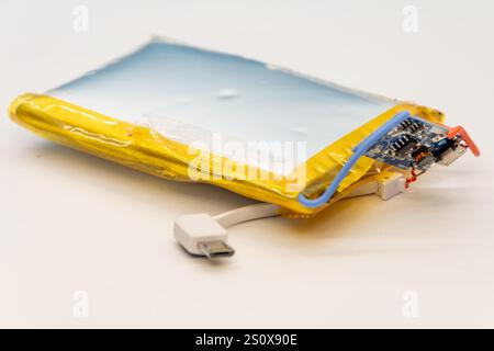 Bloated lithium-ion battery with USB connector on white background ...