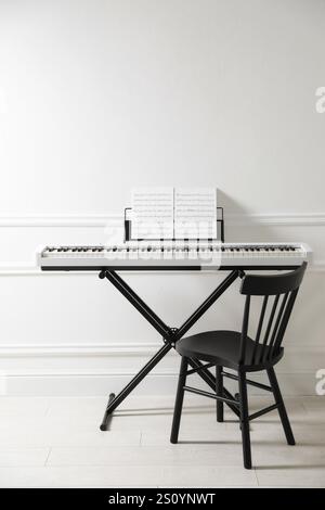 Synthesizer with music sheets and chair indoors Stock Photo - Alamy