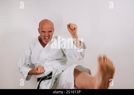 Senior karateka executing powerful kick, intense focus Stock Photo - Alamy