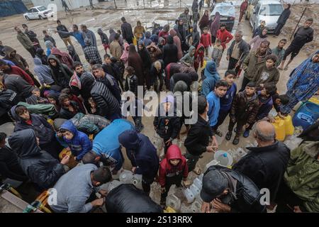 Palestinians, including children, line up to collect drinking water ...
