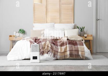 Interior of bedroom with houseplants and modern humidifier on bedside ...