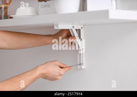 Male carpenter tightening screw in wooden table with electric ...