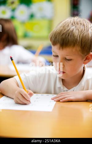 Elementary School: Problem Solving. A junior school pupil concentrating ...