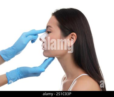 Doctor checking patient's nose after plastic surgery operation on light ...