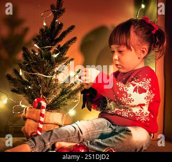 A girl decorates a Christmas tree with ornaments Stock Photo - Alamy