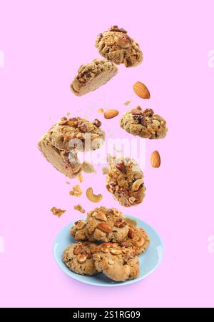 Yummy nut cookies falling onto wooden board on white background Stock ...