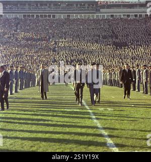 President John F. Kennedy is escorted across field by Navy men at ...