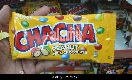 Hand holding Cha cha snack. Cha cha is peanut with milk chocolate which ...