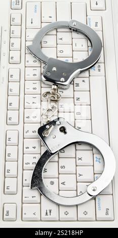 A computer keyboard and handcuffs. Cybercrime Stock Photo - Alamy