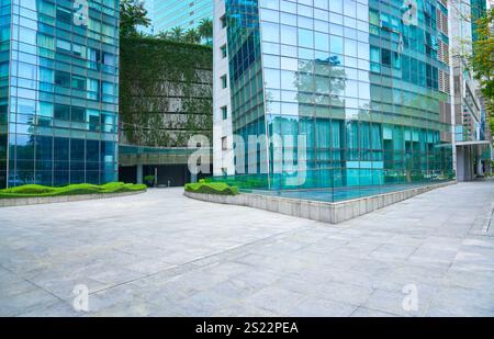 Empty square with green bushes and modern office buildings with glass ...