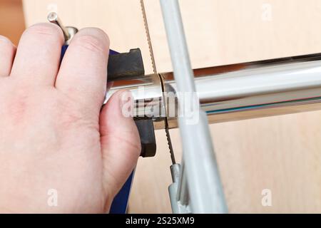 metalworker saws metal plumbing pipe gripped in vice by hacksaw close ...