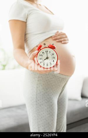 Conceptual photo of time to baby be born. Pregnant woman holding clocks ...