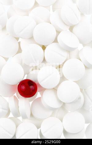 White tablets in contrast with a red tablet, symbolic photo for ...