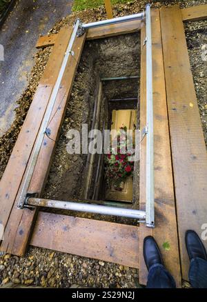 The open, fresh grave with coffin in a cemetery. After the funeral ...