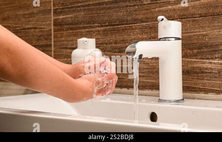 Kid using liquid soap and running water for hand washing and hygiene ...