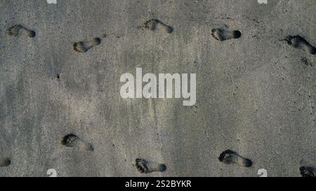 Footprints in black sand seen from above Stock Photo - Alamy