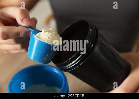 Making protein cocktail. Man adding powder into shaker at table ...