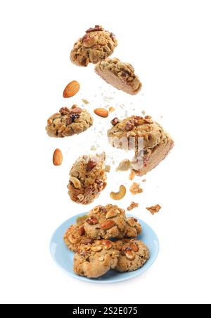 Yummy nut cookies falling onto plate on white background Stock Photo ...