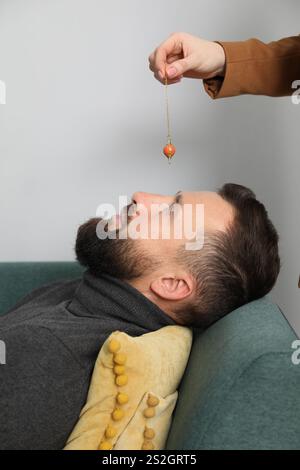Psychologist using pendulum while working with patient during hypnosis ...