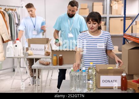 Volunteers packing donation goods at tables indoors Stock Photo - Alamy