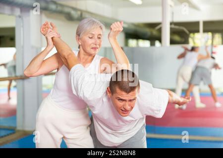 Mature woman exercising elbow strike during self-protection training ...