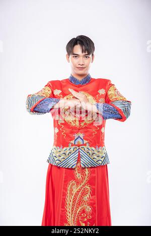 A man wear cheongsam is standing and respect customer who come to shop ...