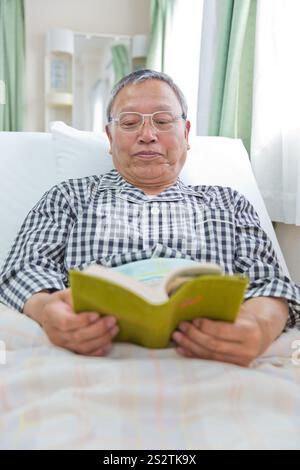 Senior male patient reading book in bed Stock Photo - Alamy
