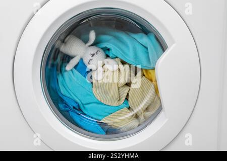 Washing machine with clothes and toy bunny as background, closeup Stock ...