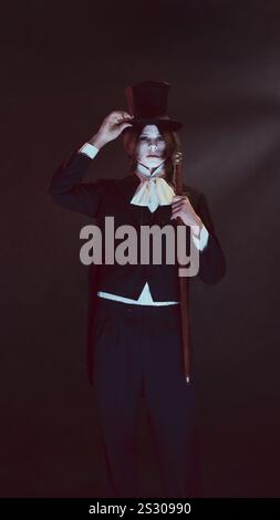 Pale-faced man, vampire, dressed in sleek black suit and top hat stands ...