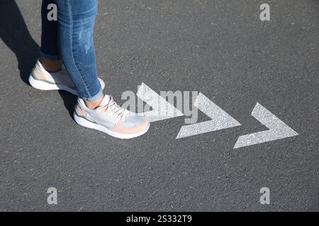 Woman walking toward white arrows pointing in different directions on ...