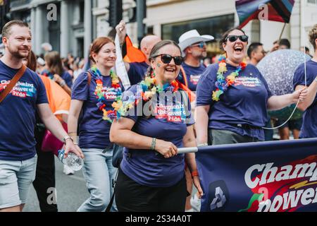 People marching at London Pride parade with rainbow flags and banners ...