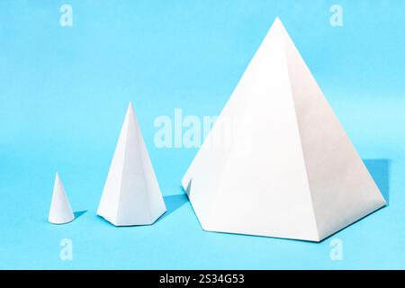 handmade various paper cone and pyramids on turquoise blue background ...