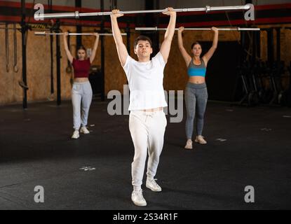 Slender guy trains muscles of arms and back using barbell and ...